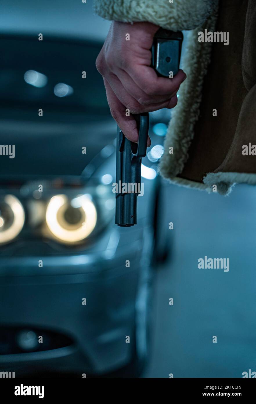 Criminal man with gun in hand in front of 7 series BMW underground ...