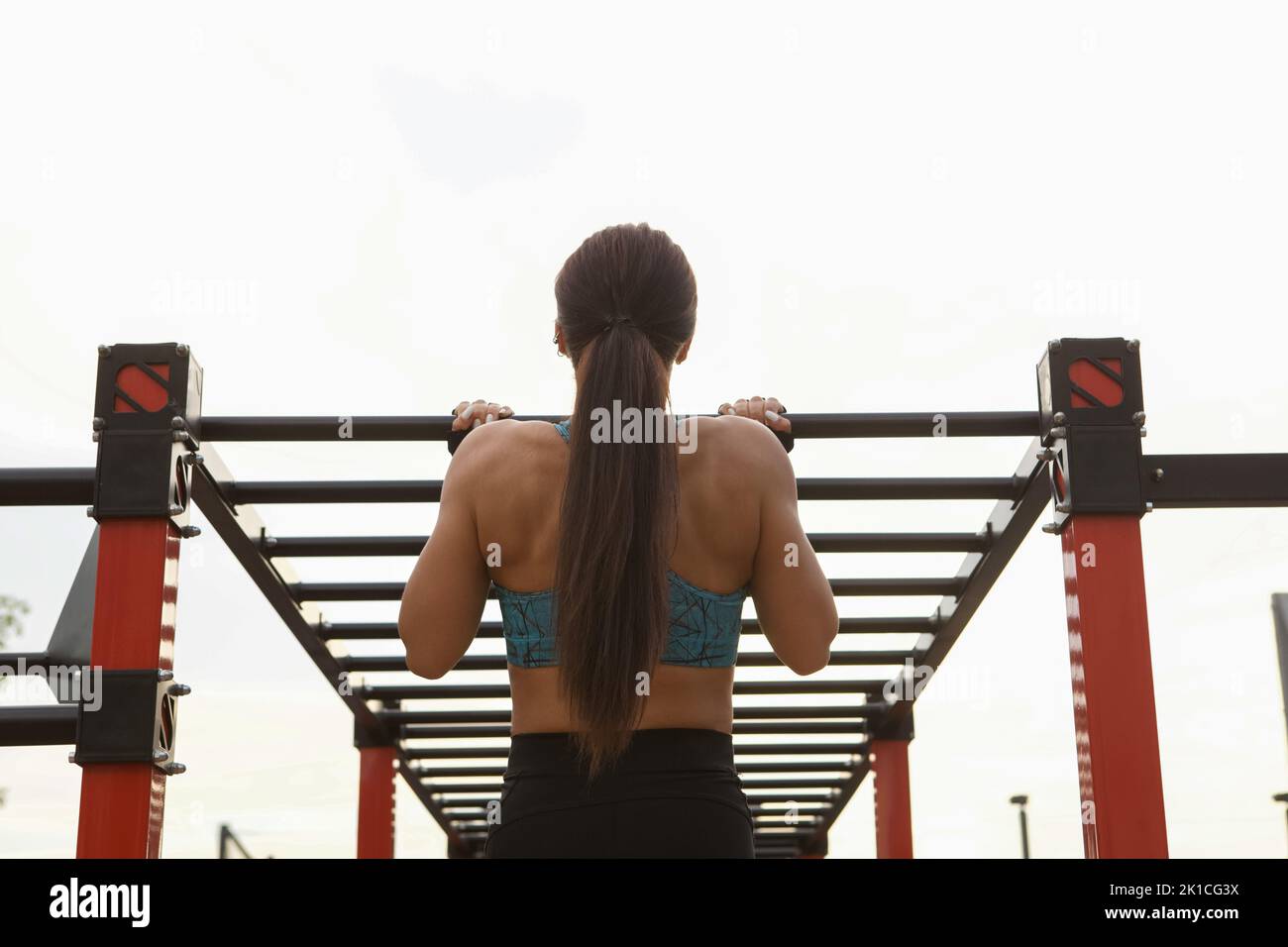 Low angle rear view shot of an athletic woman doing pull ups on ...