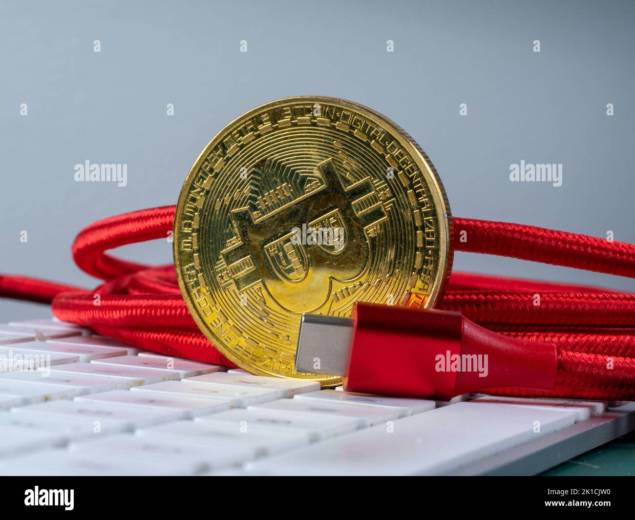 crypto coin standing vertically on a computer keyboard with red USB C ...