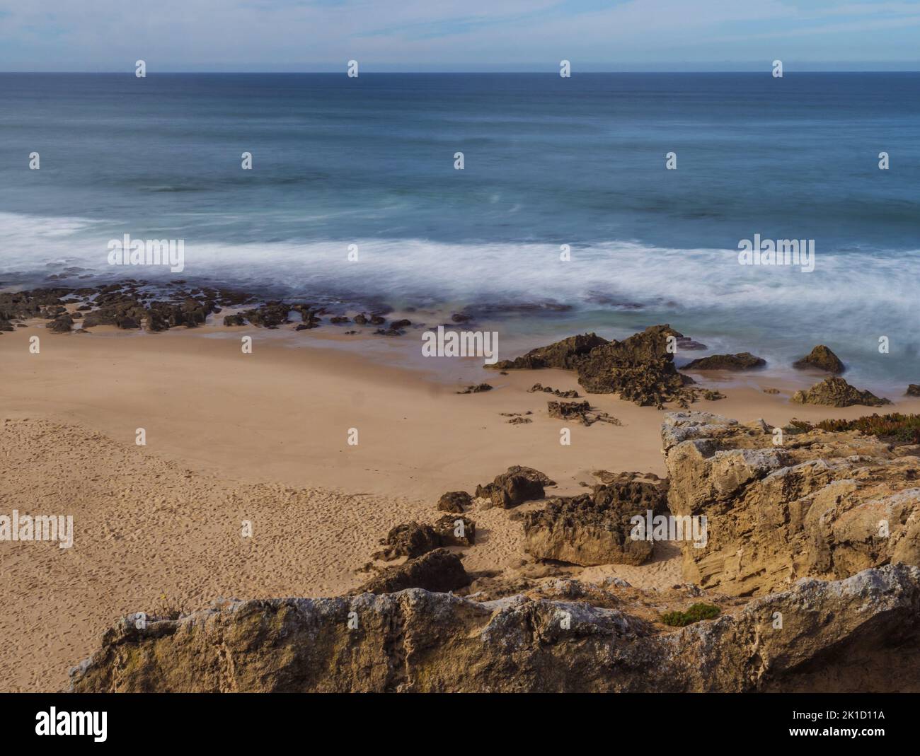 View of empty small sand beach with with long exposure blurred ocean ...