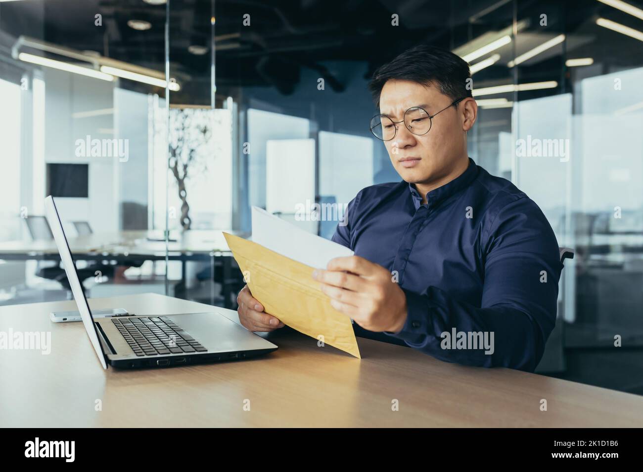 Serious and upset asian businessman reading letter with bad news ...