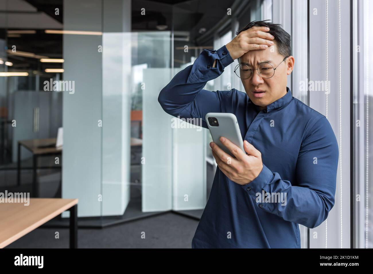 Asian businessman inside office building upset and sad reading bad news ...