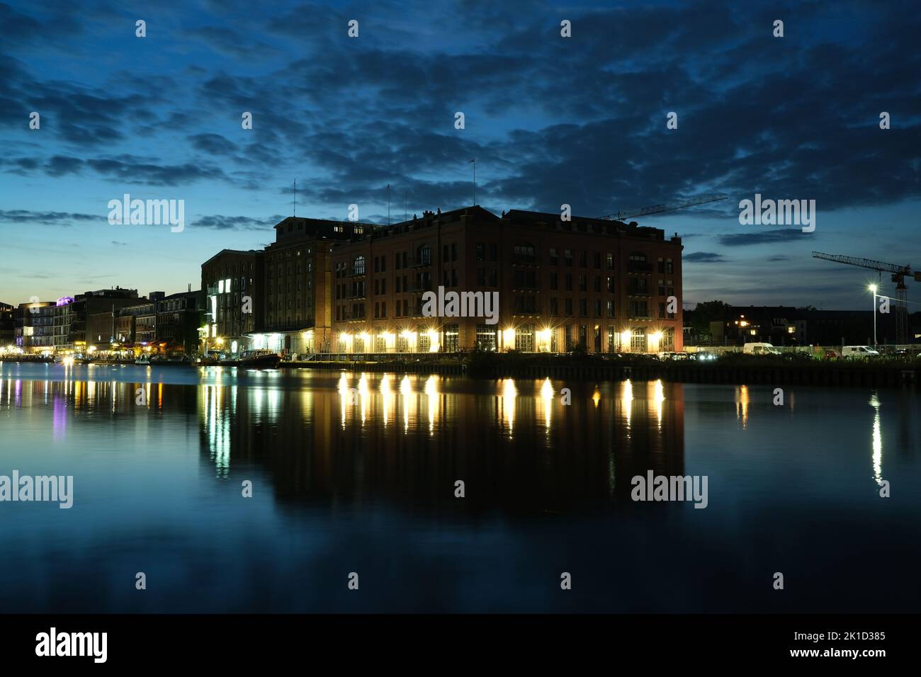 An old brick building illuminated at sunset in the harbor of Munster ...
