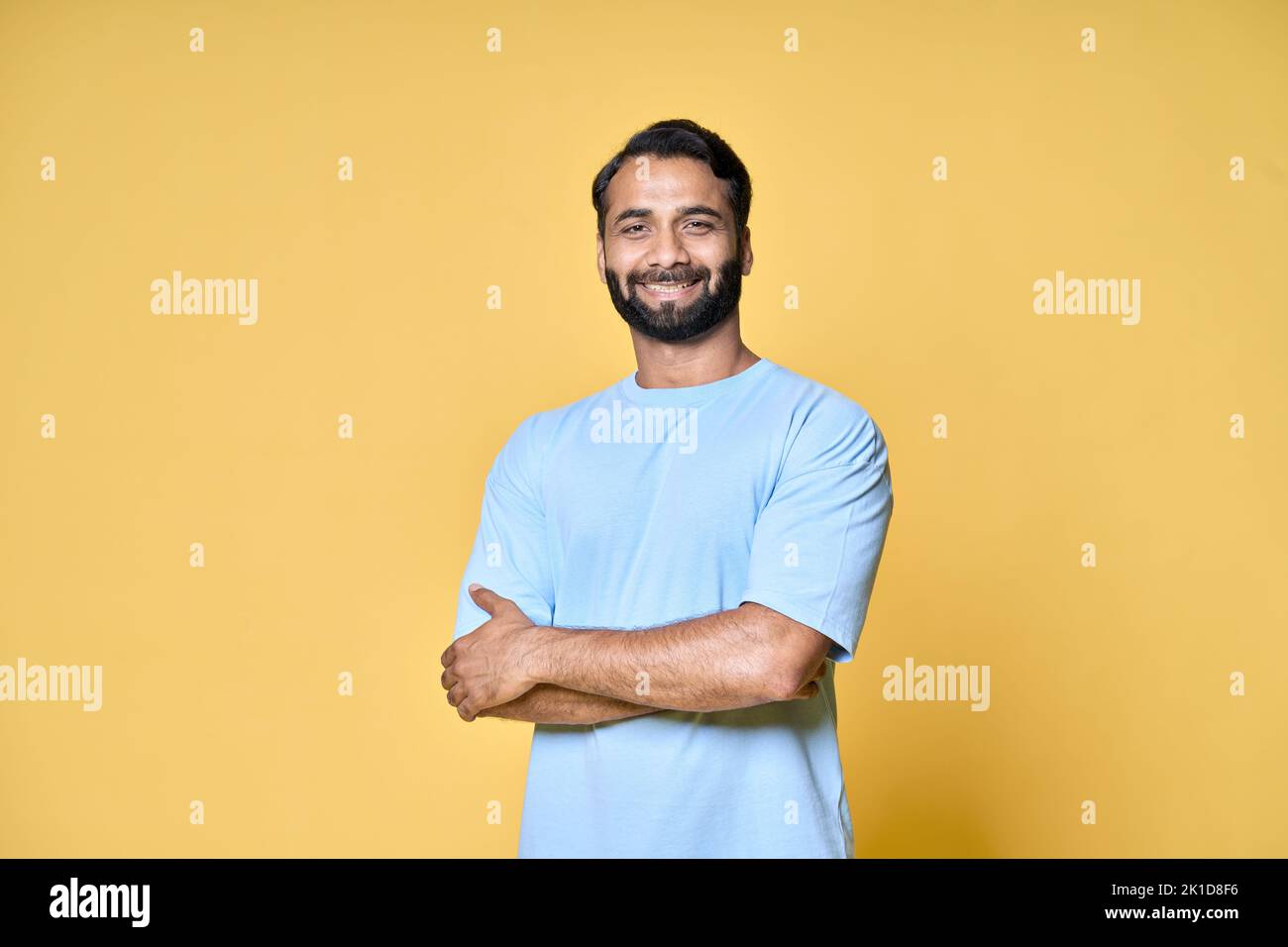 Smiling confident bearded indian man standing isolated on yellow ...