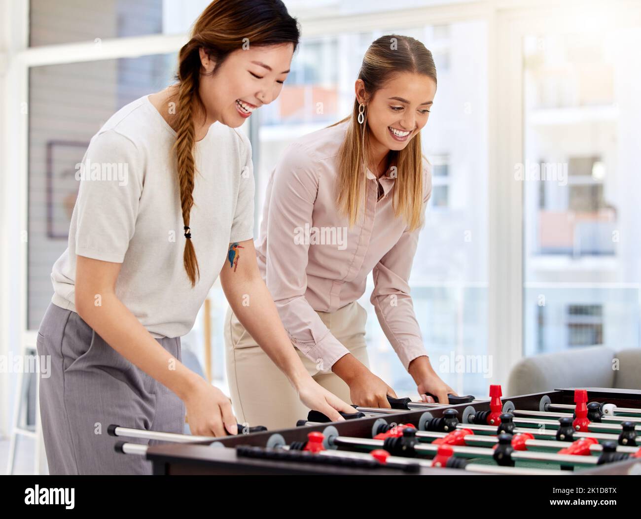 Business women playing table soccer, laughing and having office fun at ...