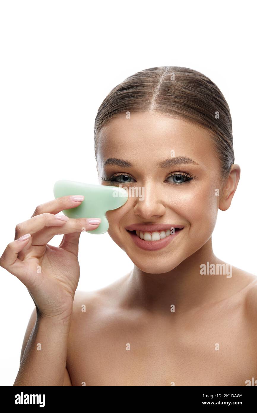 Woman with beauty face using facial gua sha. Beautiful smiling girl ...