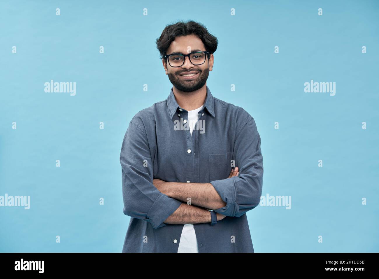 Smiling confident arabic young man standing isolated on blue background ...