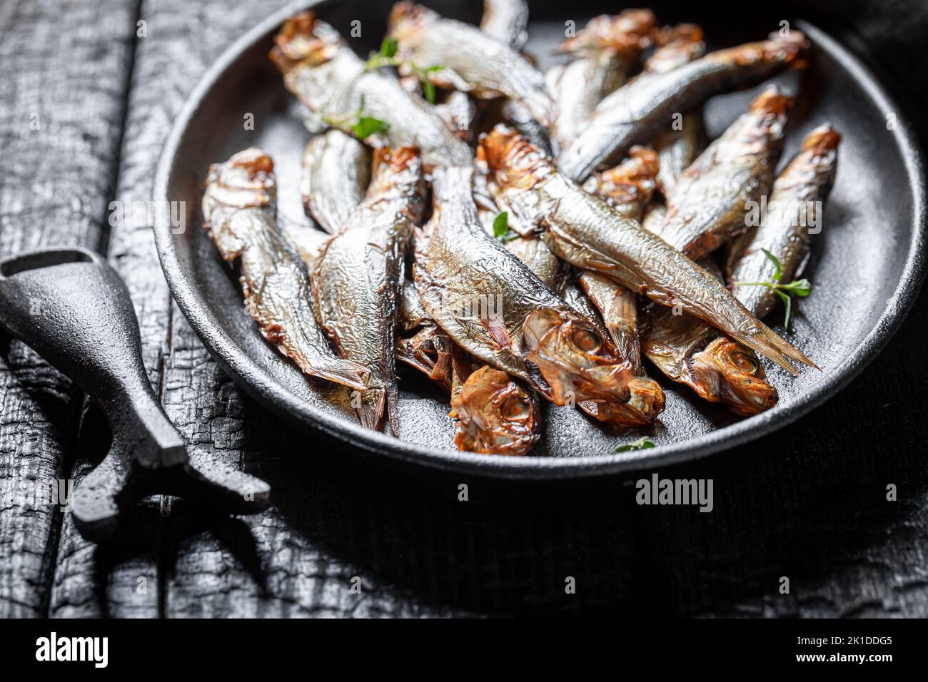 Healthy smoked sprats on a black plate and burnt table. Smoked fish ...