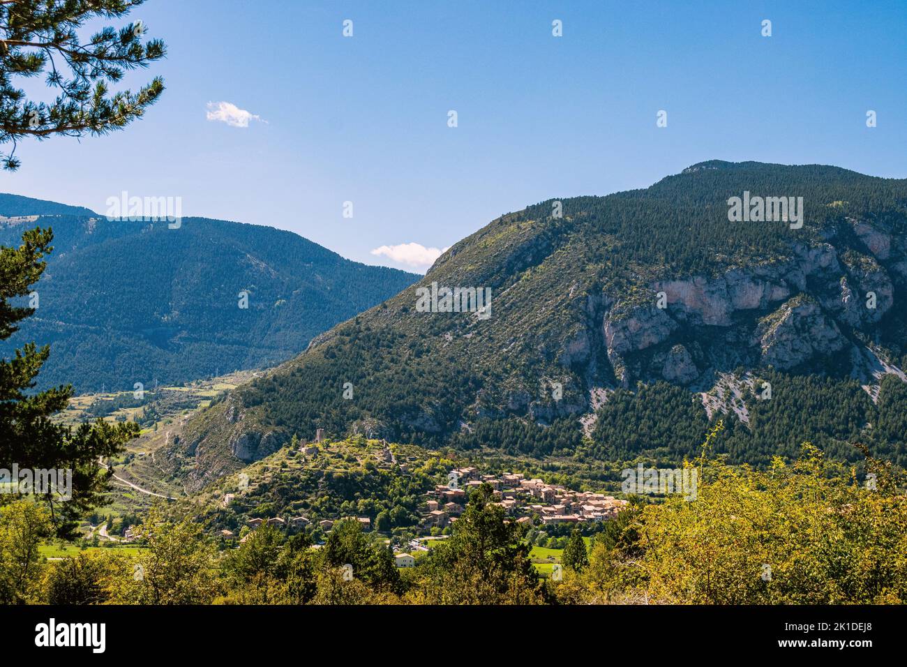 A beautiful scene of Pedraforca mountain on grass fields under blue sky ...