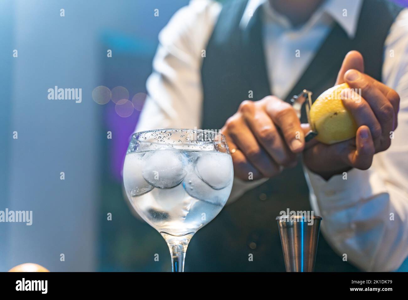 Professional barman in a white shirt and black apron making cocktail ...