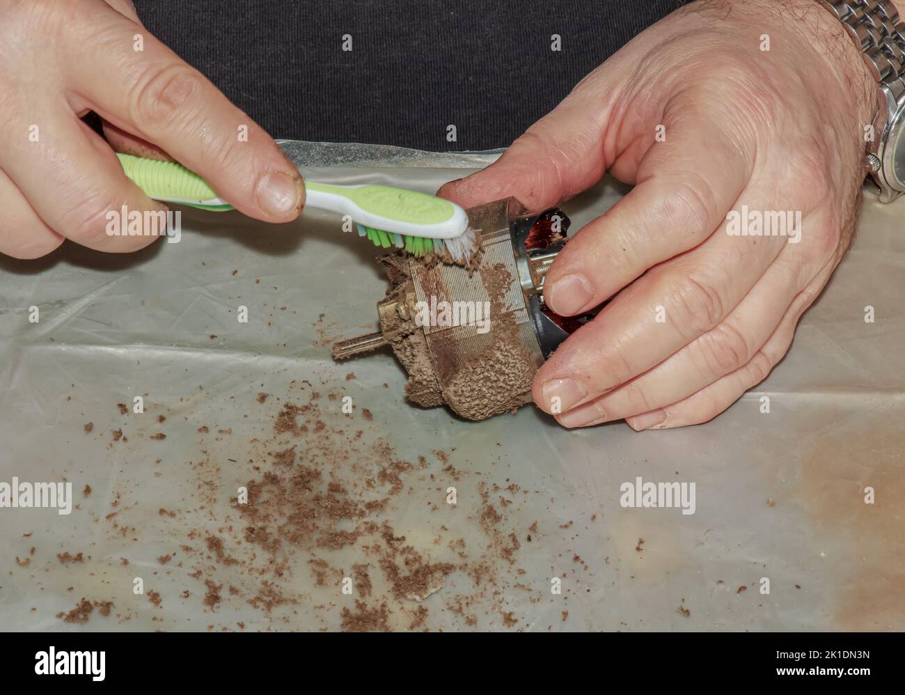 Cleaning a very dirty kitchen exhaust fan from dirt with a brush. A man ...