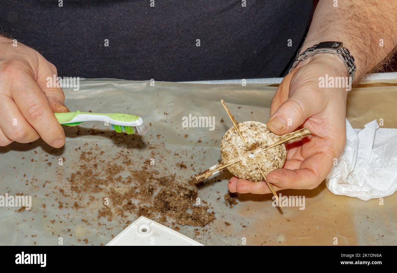 Cleaning a very dirty kitchen exhaust fan from dirt with a brush. A man ...