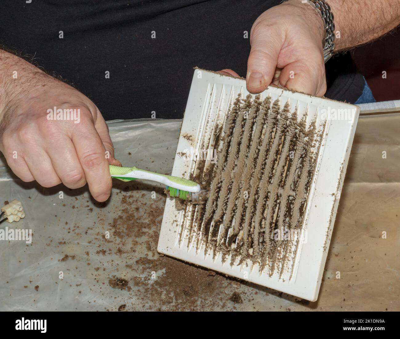 Cleaning a very dirty kitchen exhaust fan from dirt with a brush. A man ...