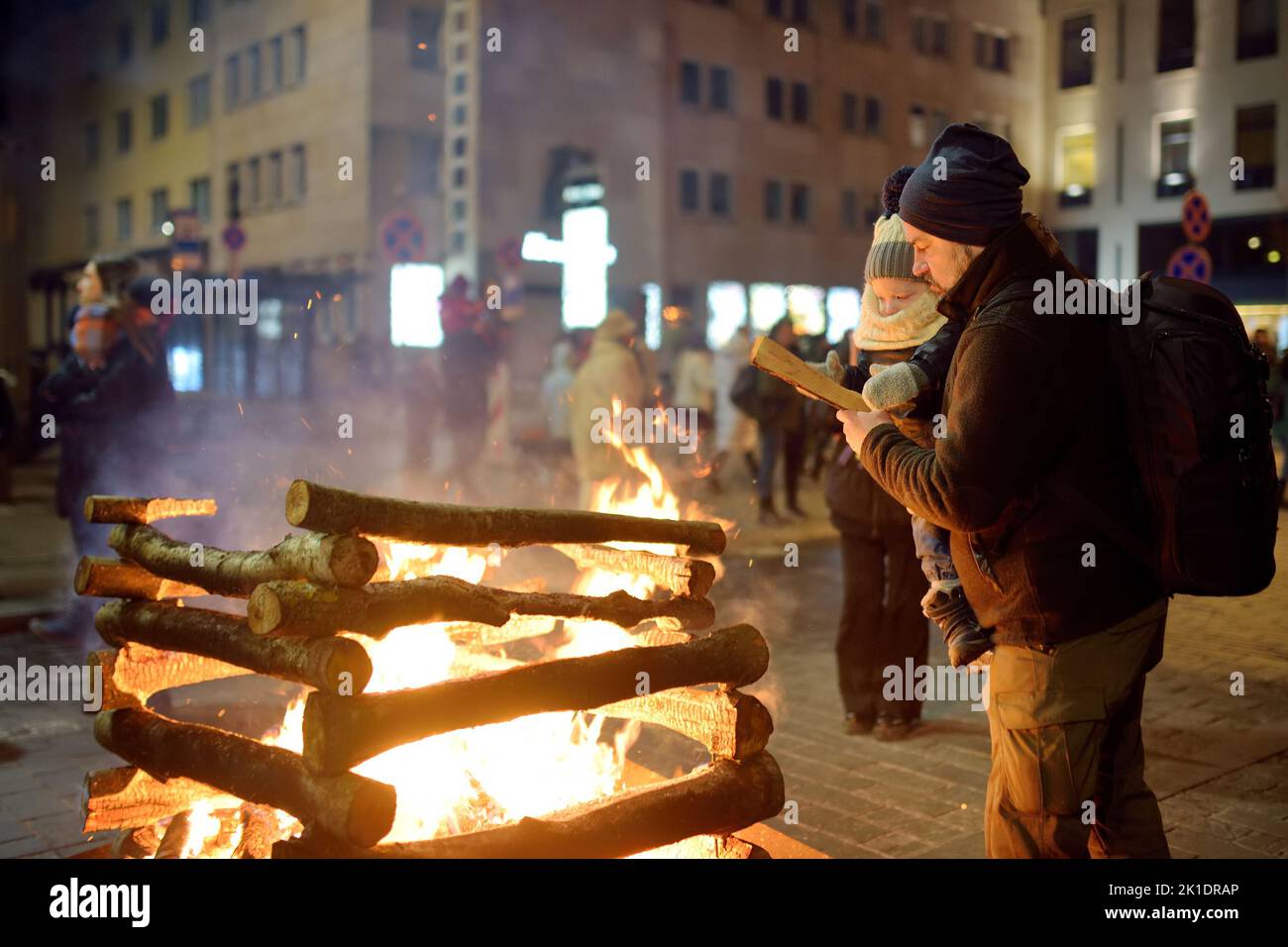 Father and son throwing a log into fire at the celebration of ...