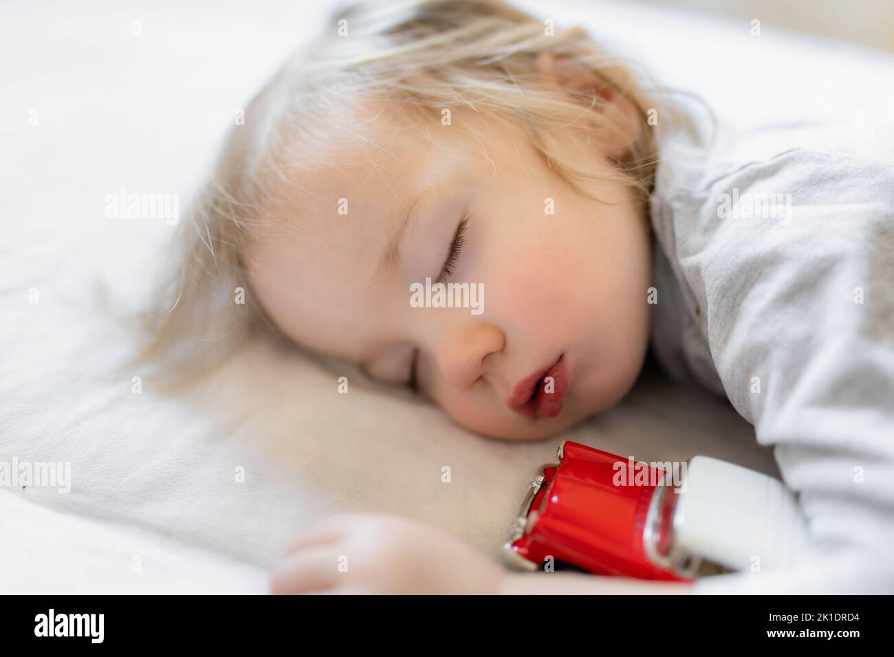 Adorable toddler boy sleeping in bed with his toy car. Tired child ...