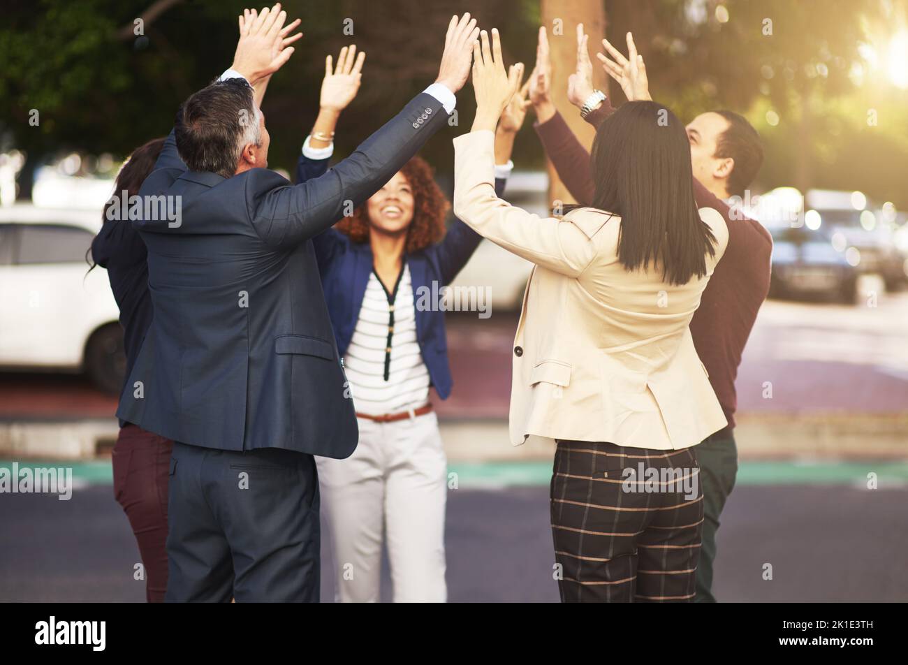 We did it. a group of colleagues high fiving outside Stock Photo - Alamy