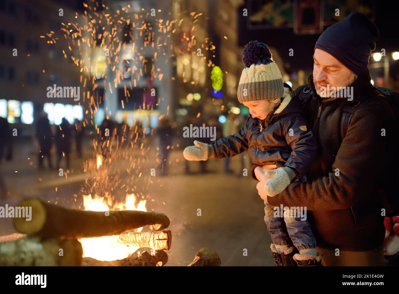 Father and son throwing a log into fire at the celebration of ...