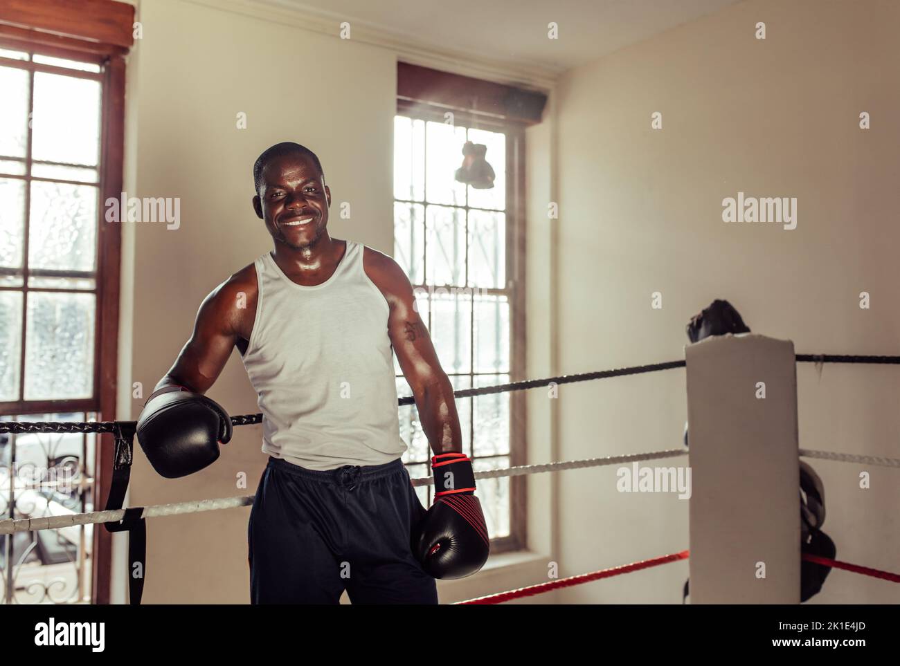 Happy young boxer smiling at the camera while standing in a boxing ring ...