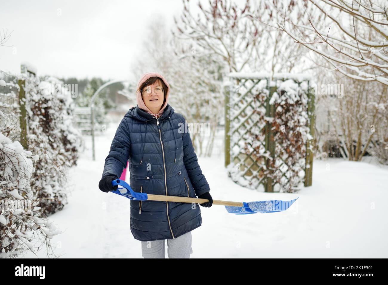 Senior woman shoveling snow off a walkway after massive snowfall ...