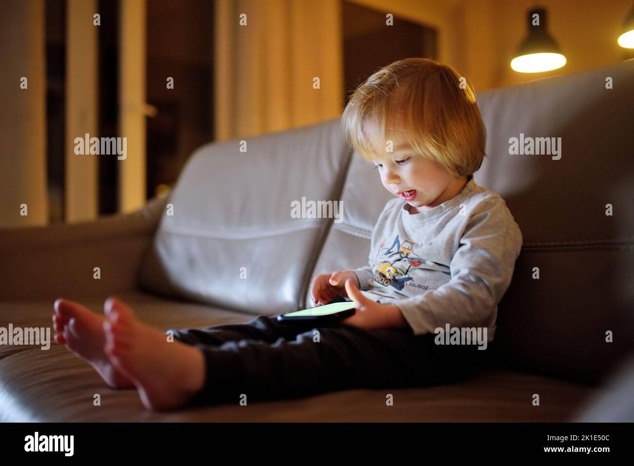 Adorable toddler boy playing with a smartphone in a dark room. Child ...