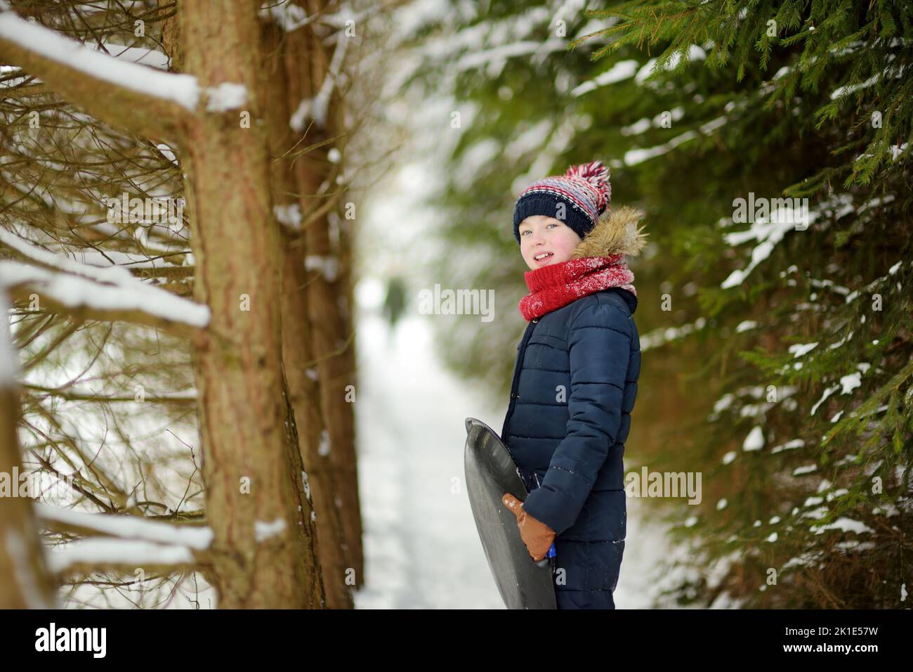 Cute young girl having fun on a walk in snow covered pine forest on ...
