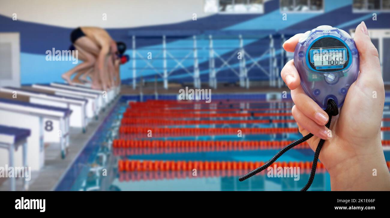 Close up of a hand holding a timer on a white background against swimmers ready to plunge Stock ...