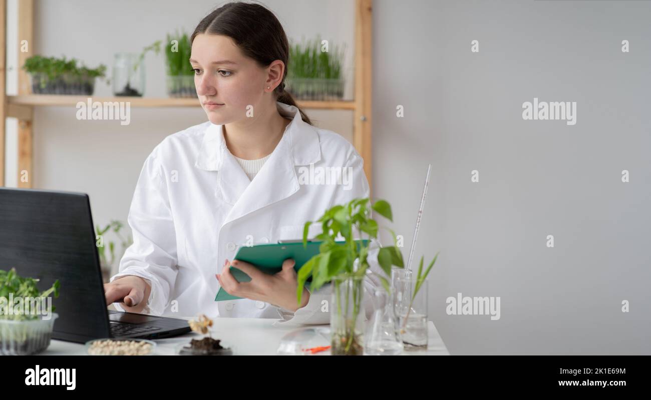 Handsome female microbiologist with healthy green plant at lab. Medical scientist working in a ...
