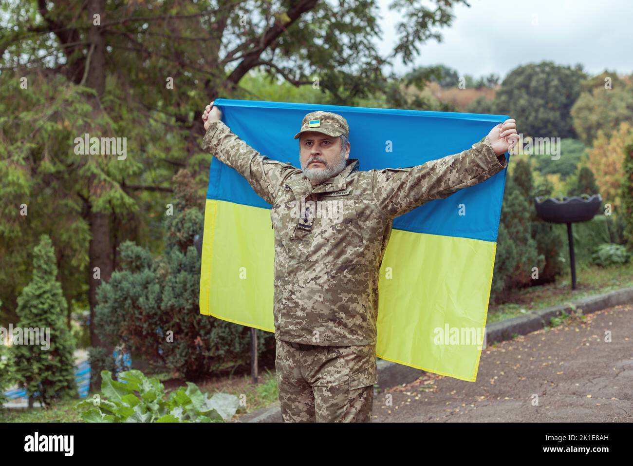The Ukrainian military man holds the flag of Ukraine in his hands. War ...