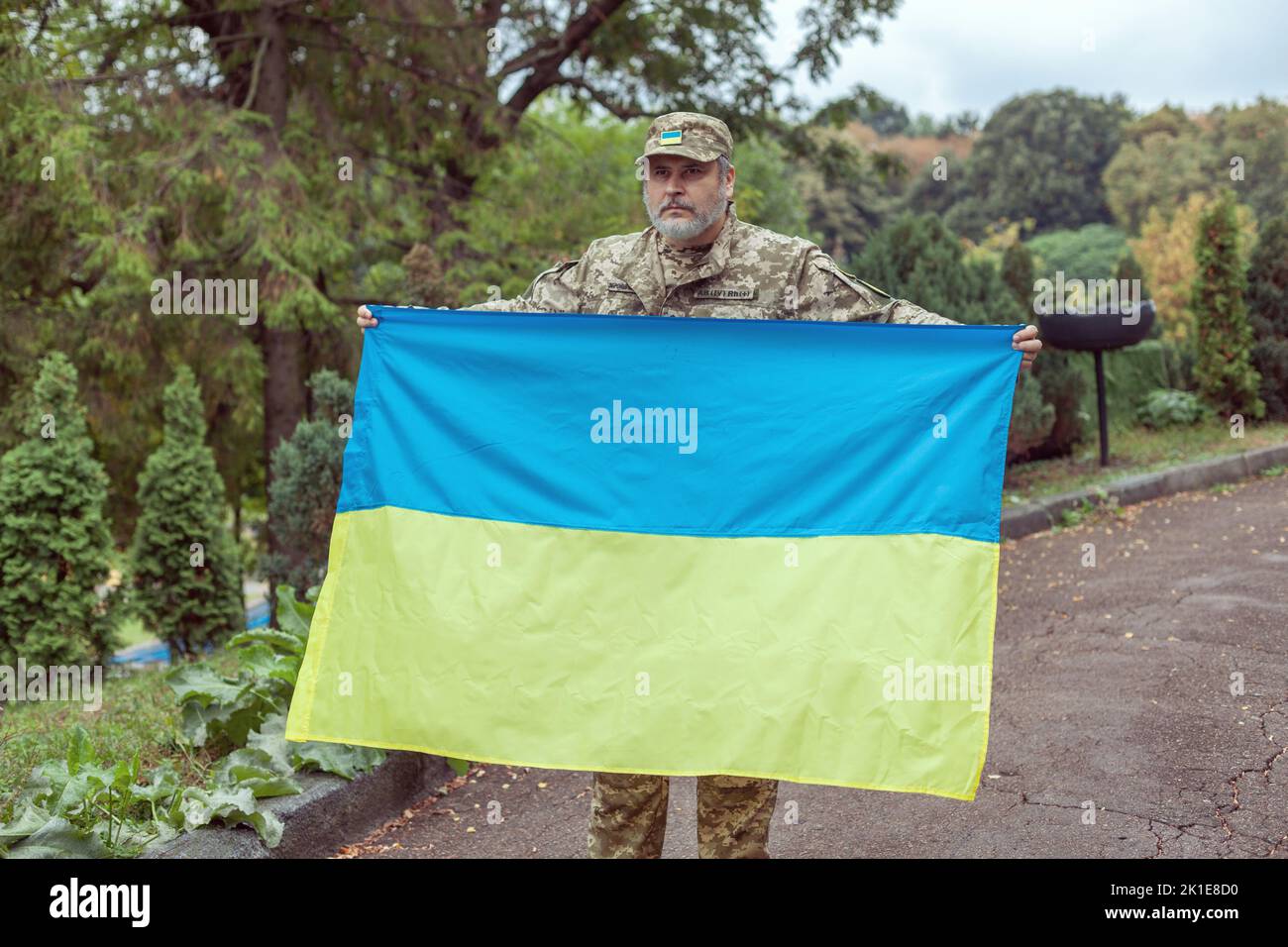 The Ukrainian military man holds the flag of Ukraine in his hands. War ...