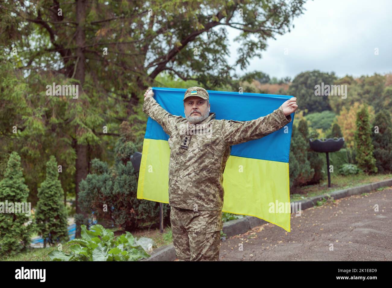 The Ukrainian military man holds the flag of Ukraine in his hands. War ...
