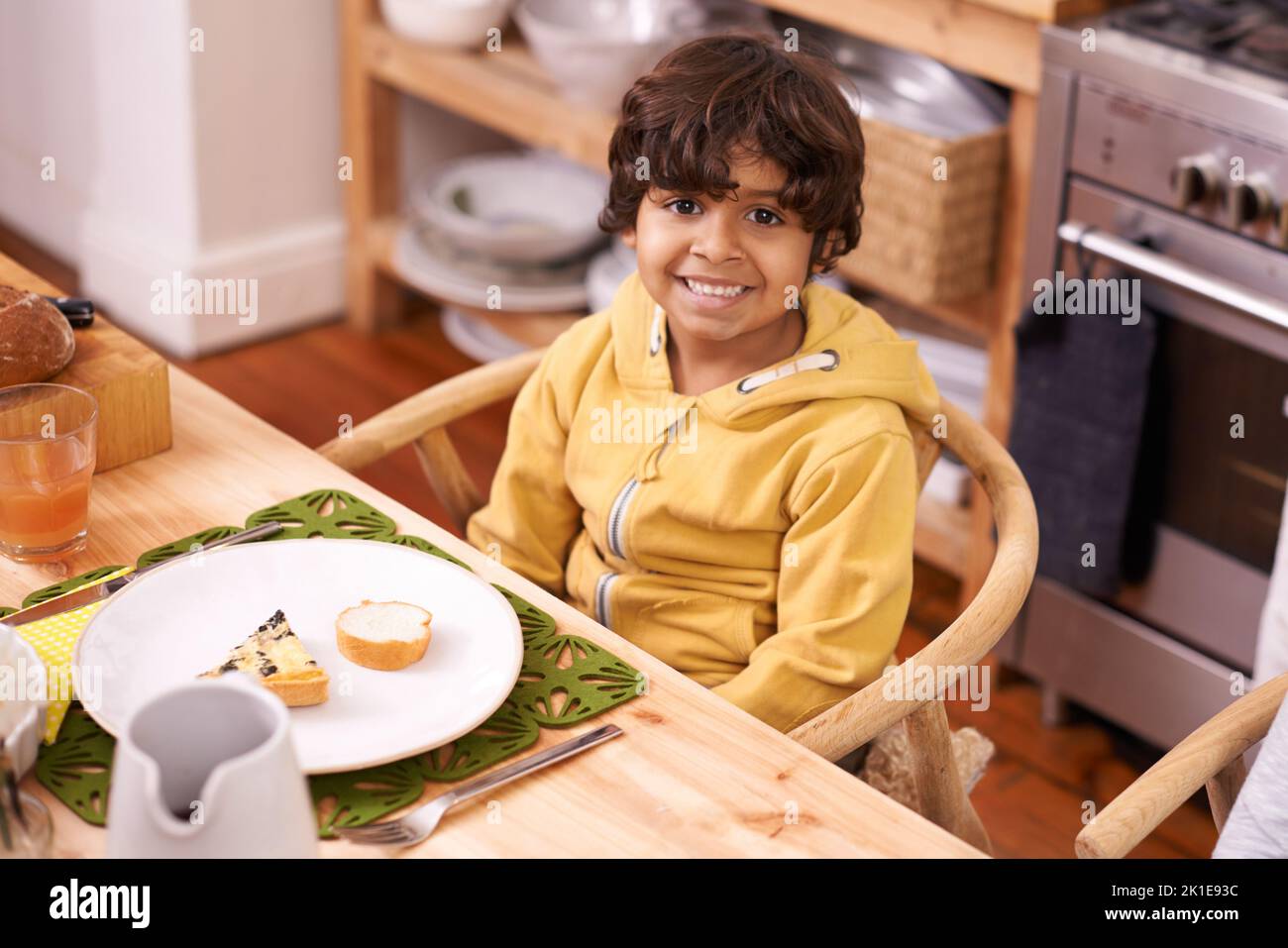 I love moms cooking. A portrait of a cute young boy sitting at the ...