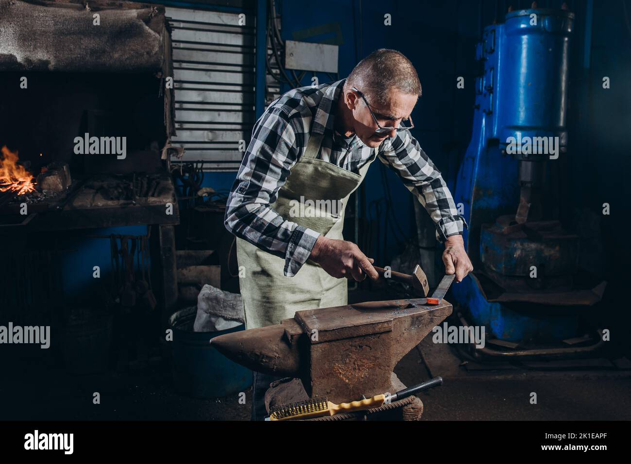 The blacksmith manually forging the red-hot metal on the anvil in ...