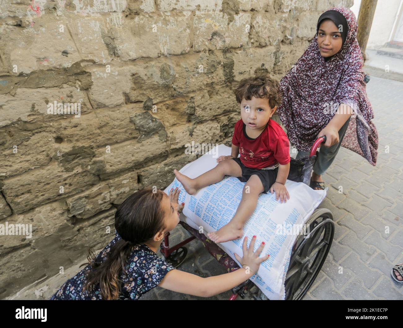 Palestinian children pull a cart loaded with sacks of flour received by ...