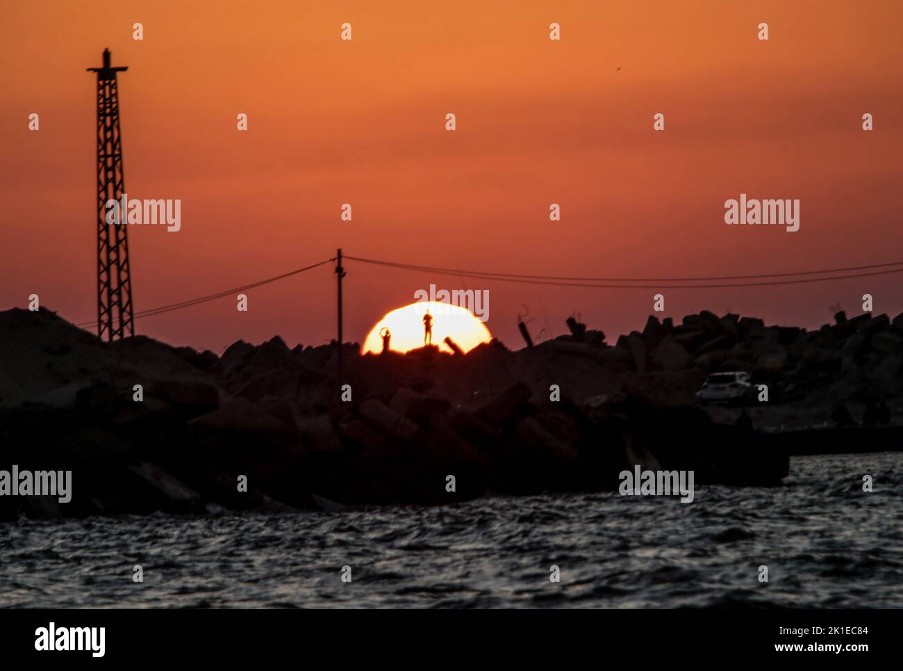Palestinians walk in front of a sunset in Gaza City. (Photo by Mahmoud ...