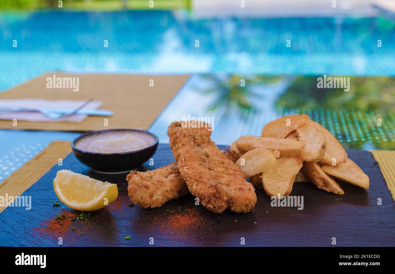 Fish and chips on a plate isolated by the pool. fish and chips with ...
