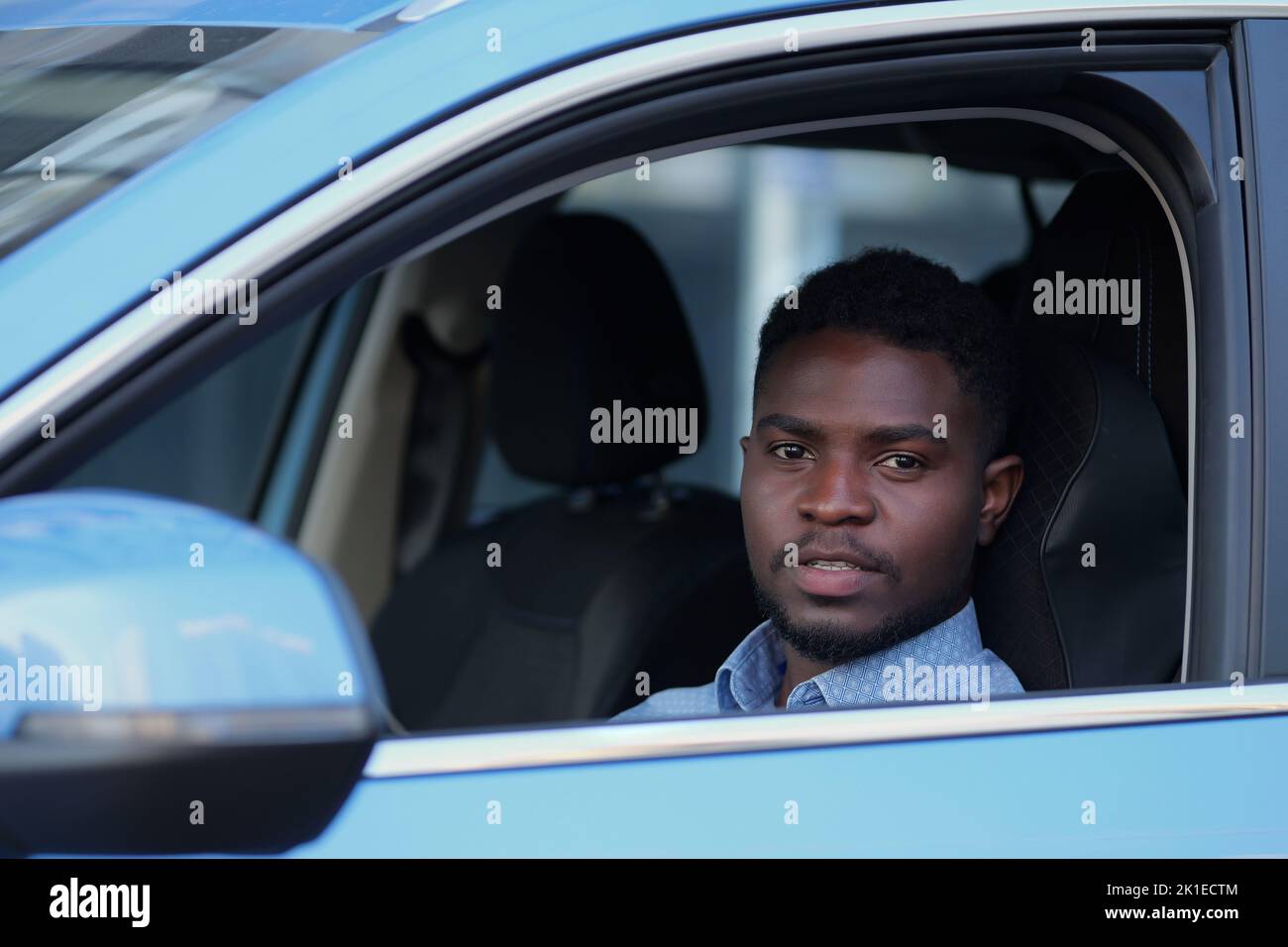 African American driver sits in black cabin of blue car Stock Photo - Alamy