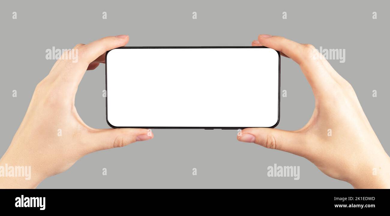 Hands holding phone mockup in horizontal position on grey background ...