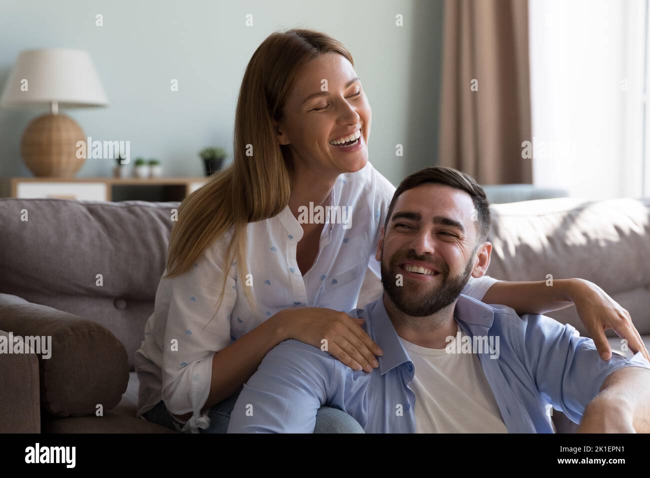 Joyful married couple talking and laughing in living room Stock Photo ...
