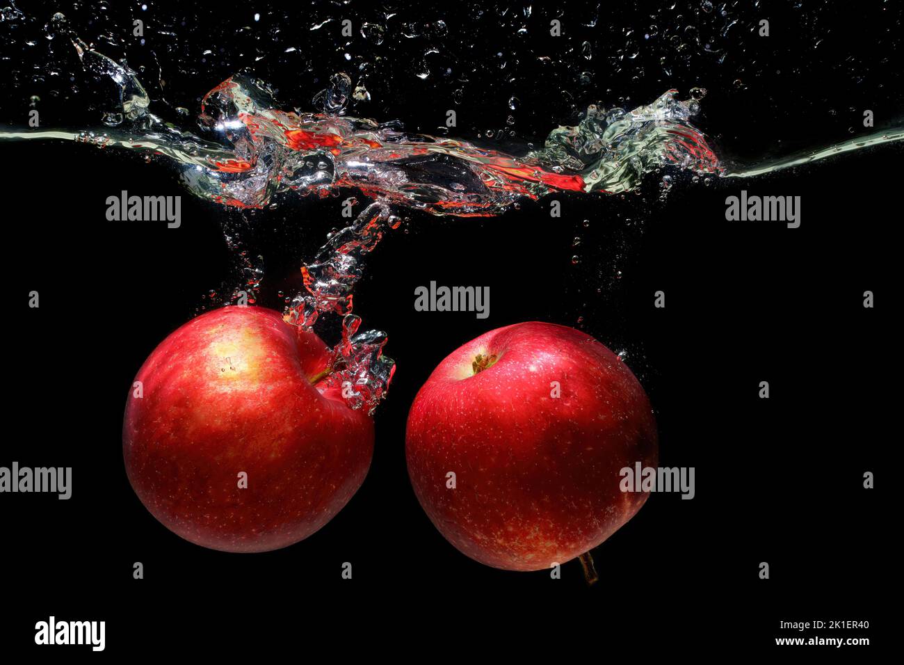Pair of red apples dropped in water with bubbles and splashes isolated ...