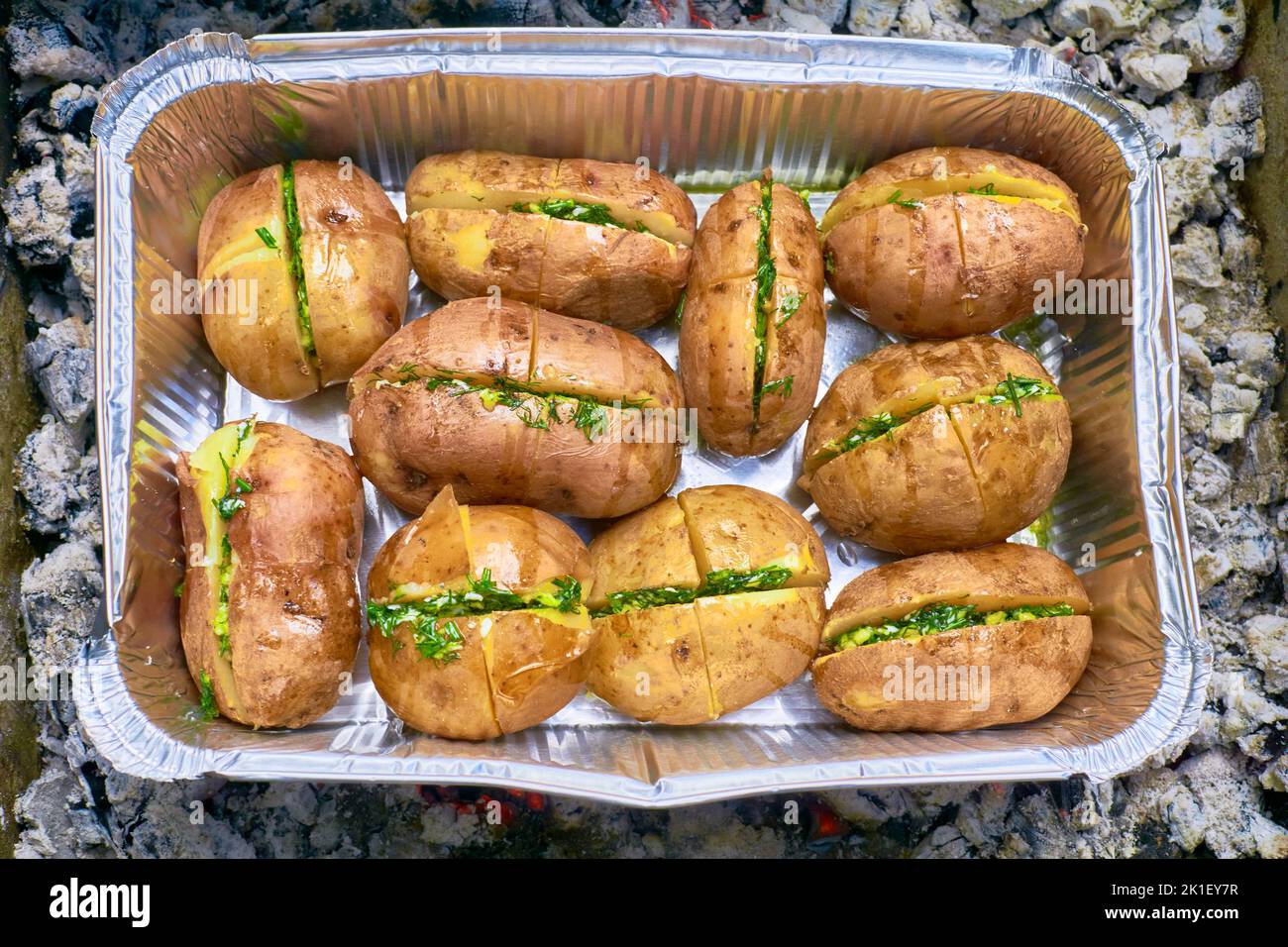 Baked potatoes with herbs and spices in a metal foil container Stock ...