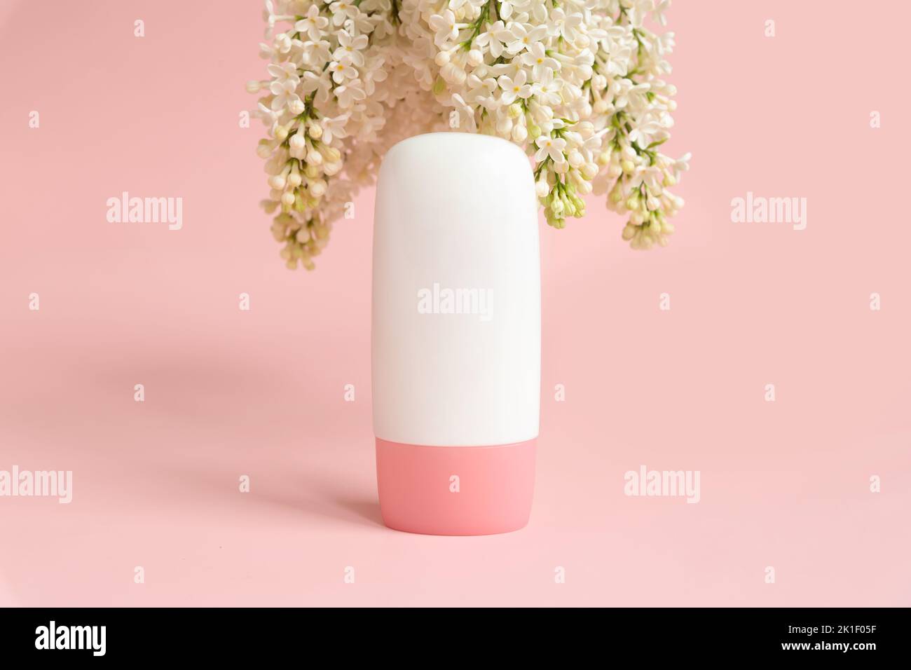 Mockup white cosmetic tube bottle with pink screw cap and white lilac ...