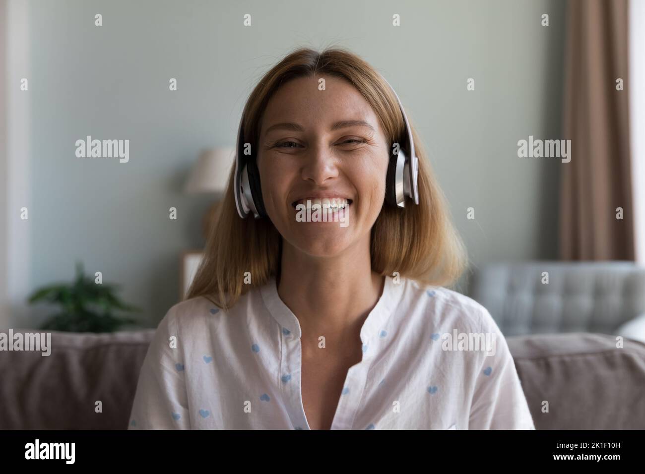 Cheerful happy pretty Caucasian woman wearing wireless headset head ...