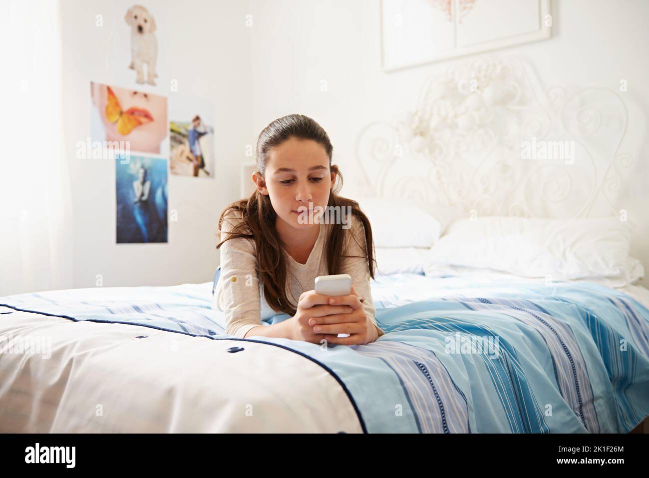 Connection is everything. a teenage girl lying on her bed and texting ...