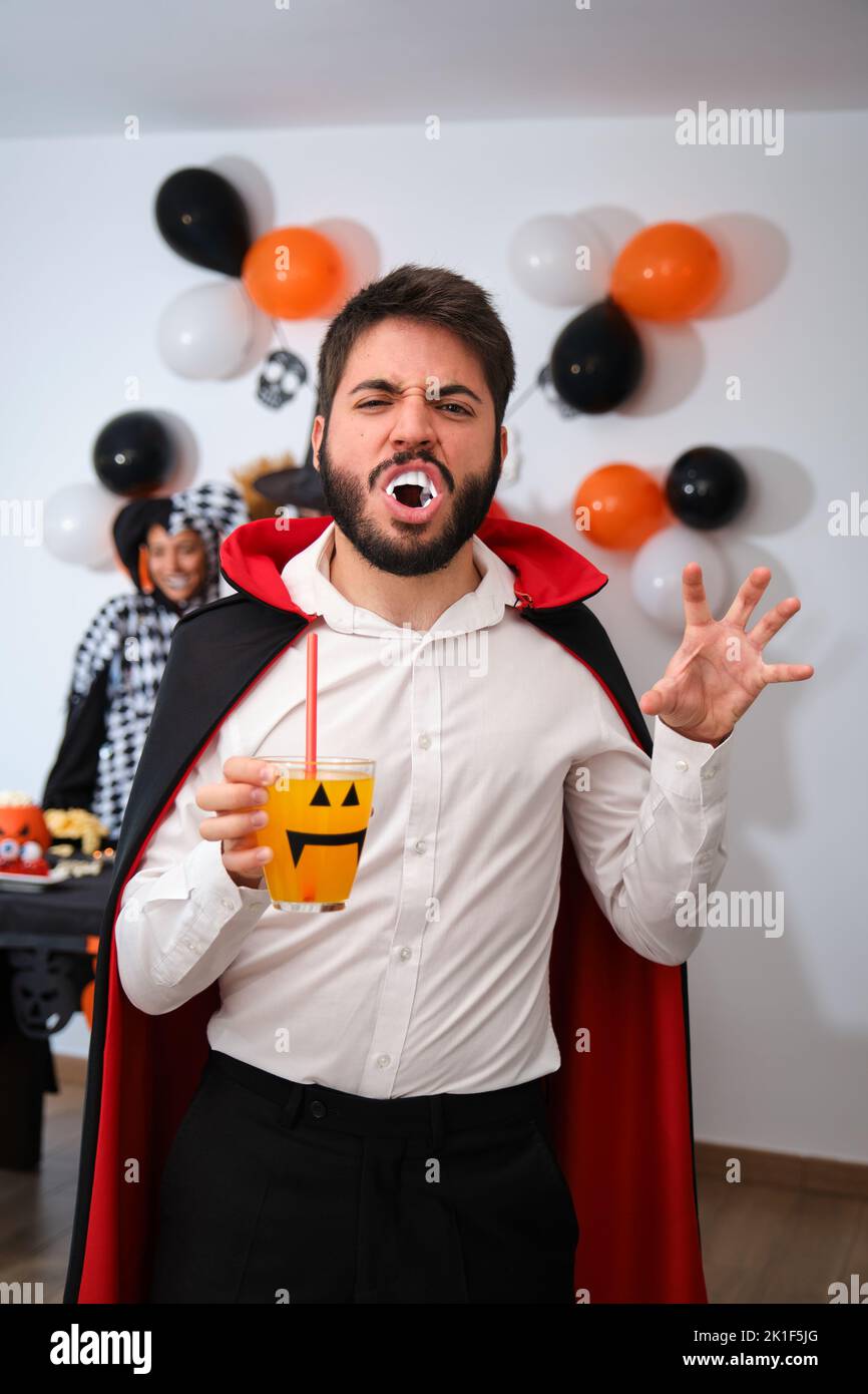Young man dressed as vampire with a cocktail at costume Halloween party ...