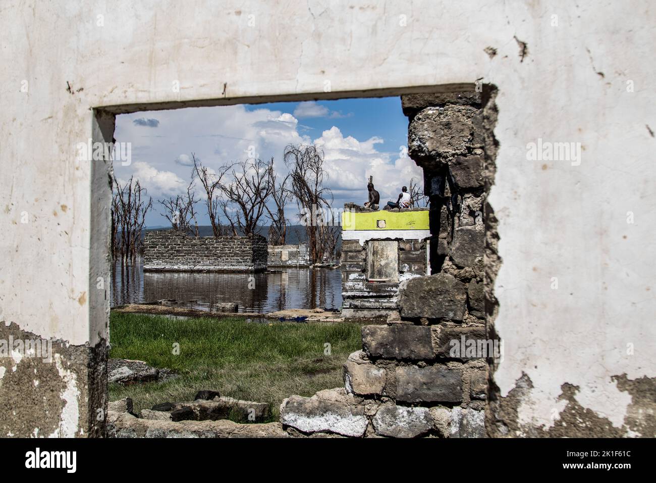 Two boys sit on top of a submerged stone following the rising lake ...