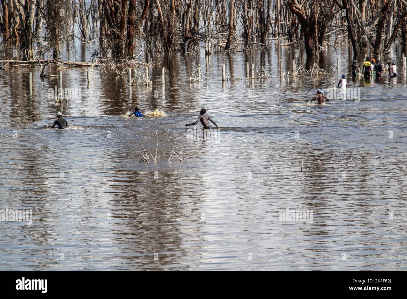 Men lay their fishing nets near the submerged fence that separated Lake ...
