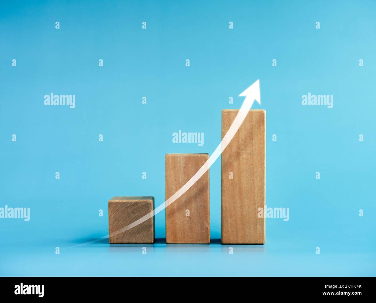 Shining rise up arrow on wooden cube blocks, bar graph chart steps on blue background, profit ...
