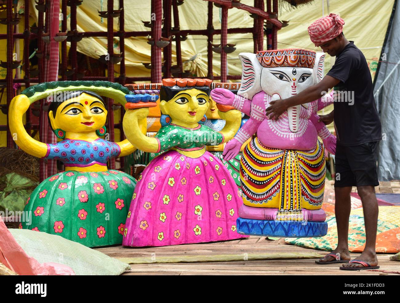 An artisan is carrying a Hindu lord Ganesha model inside a pandal or a ...