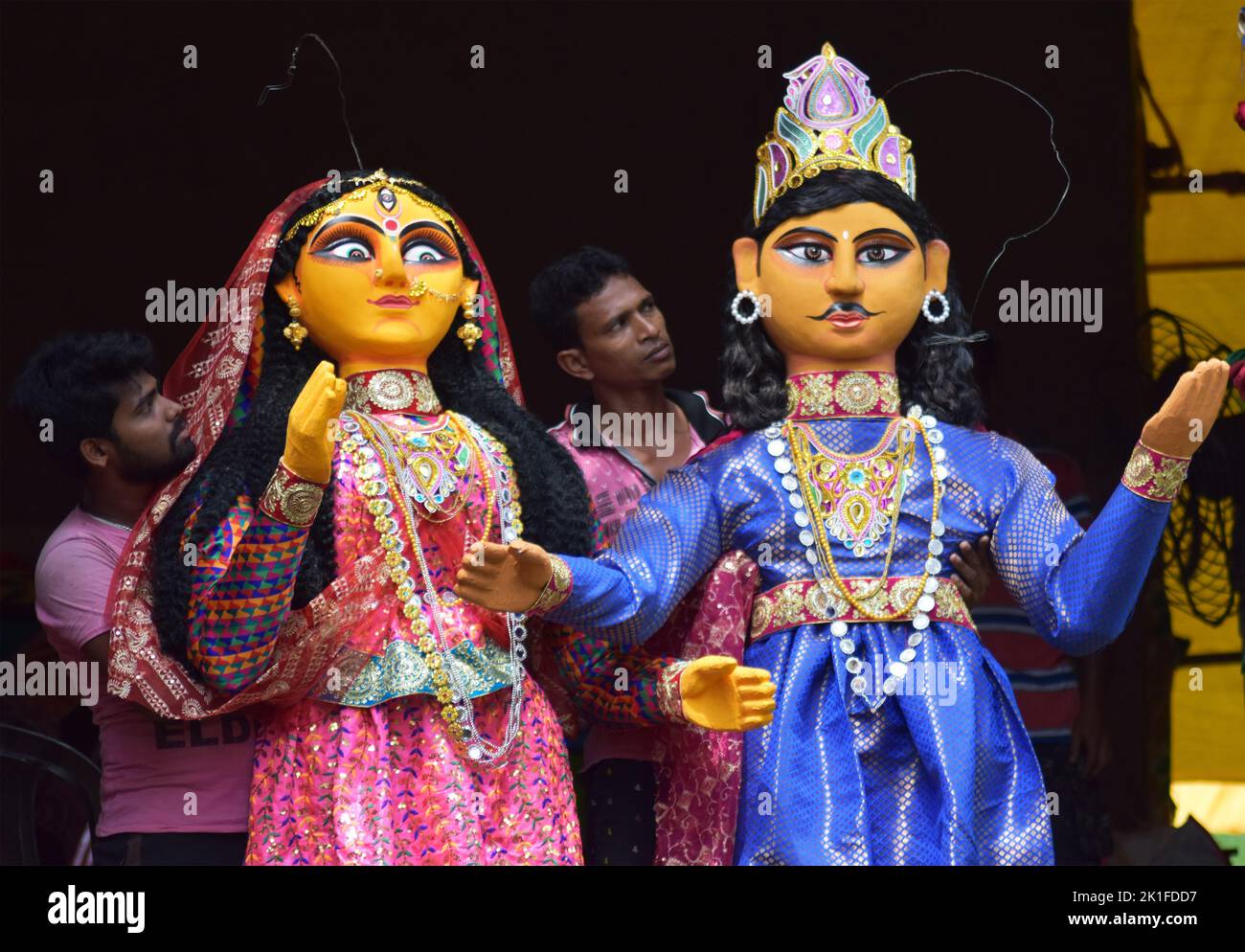 Artisans are carrying puppets inside a pandal or a temporary platform ...