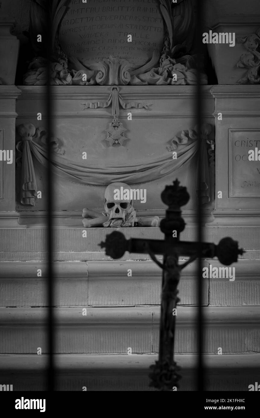 Skeleton head and bones beyond bars with a religious cross as sign of ...